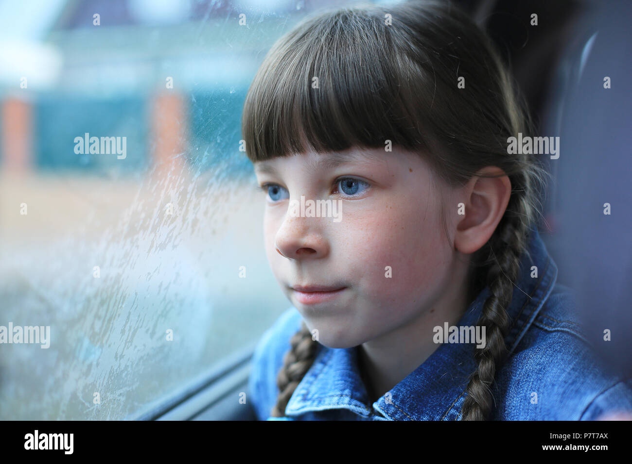 little girl with blue eyes sitting in the back of the car at the window ...