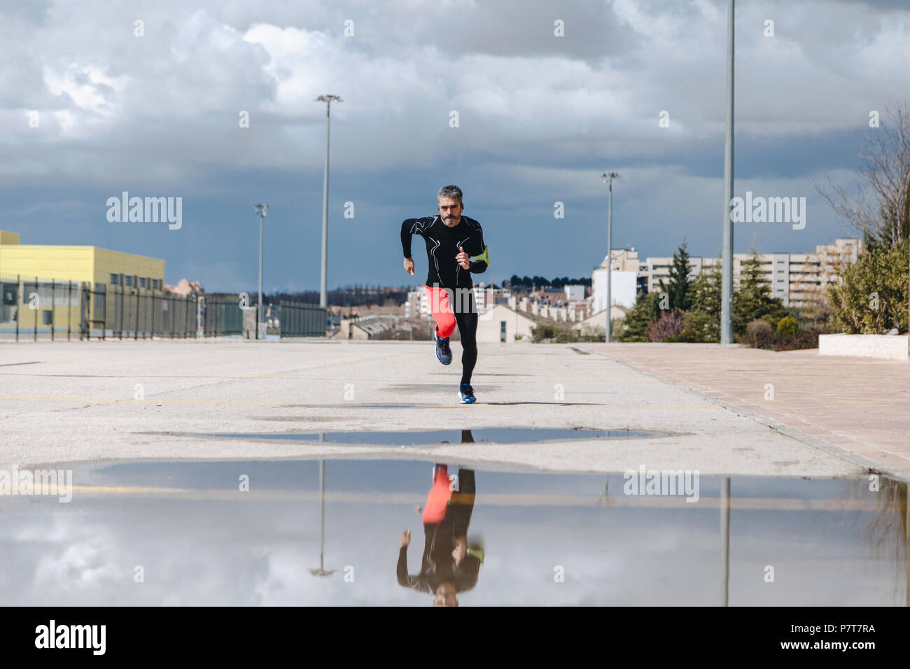 young adult man running in the street after rain over a puddle Stock ...