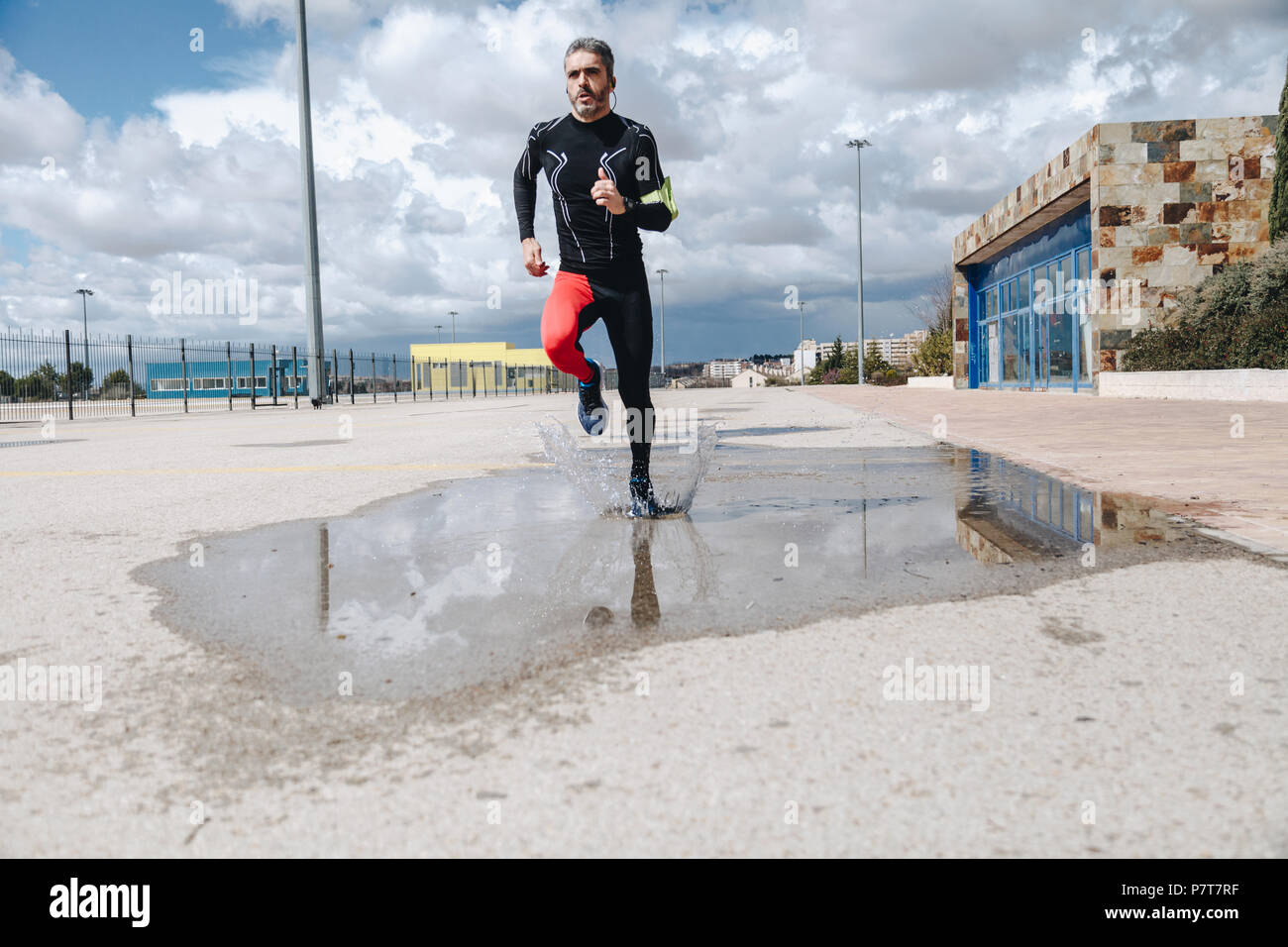 young adult man running in the street after rain over a puddle Stock ...