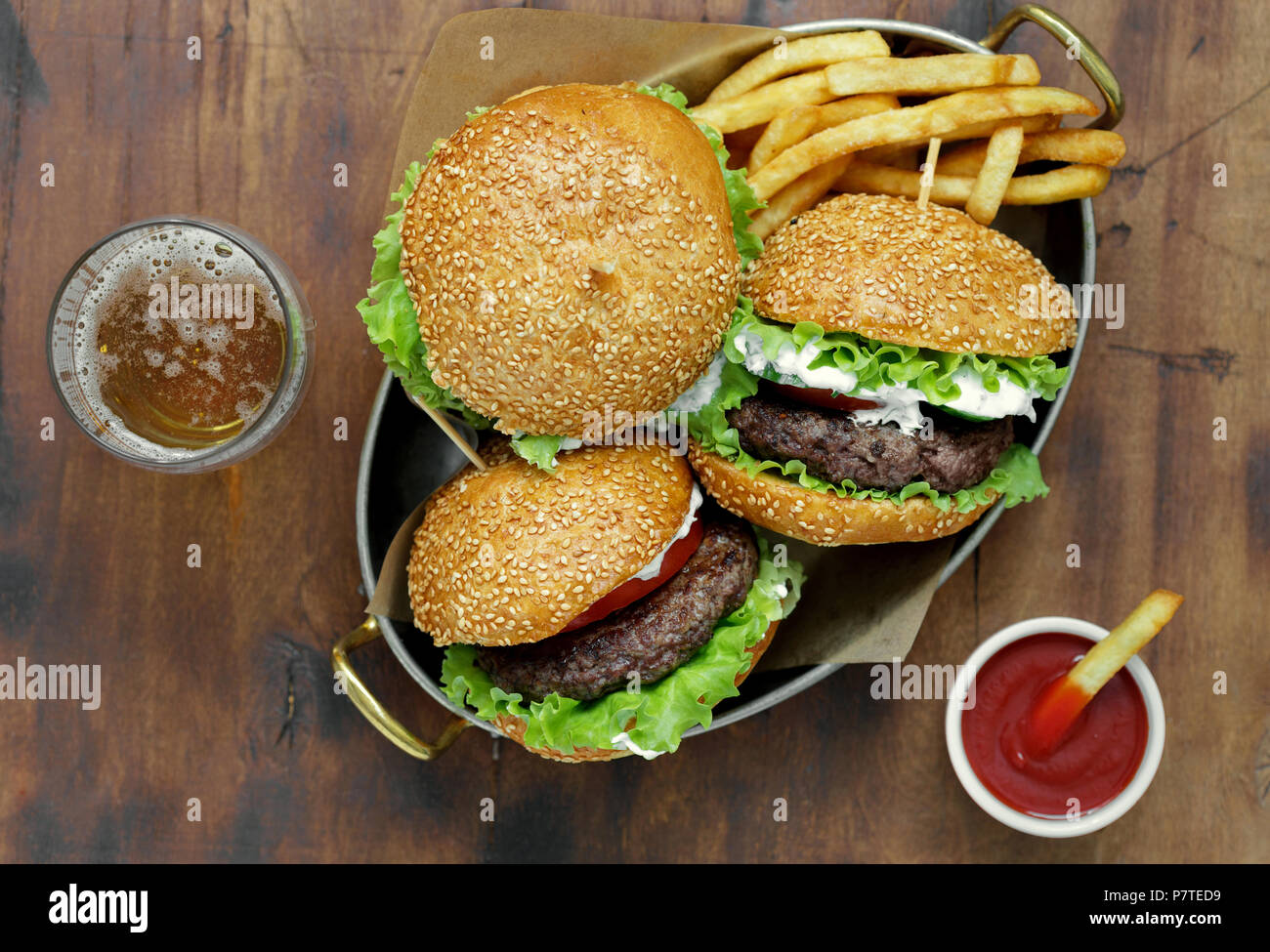 Burgers with beef cutlets and french fries are served in a frying pan ...