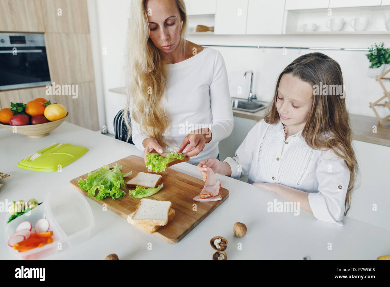 Mother with daughter preparing school lunch in home kitchen Stock Photo ...