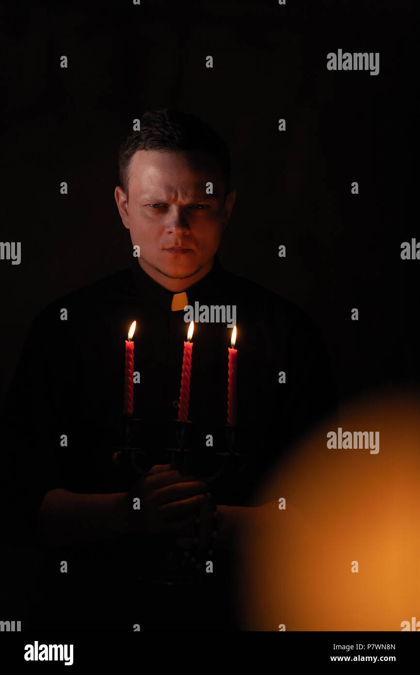 Portrait of handsome catholic priest or pastor with dog collar, dark ...