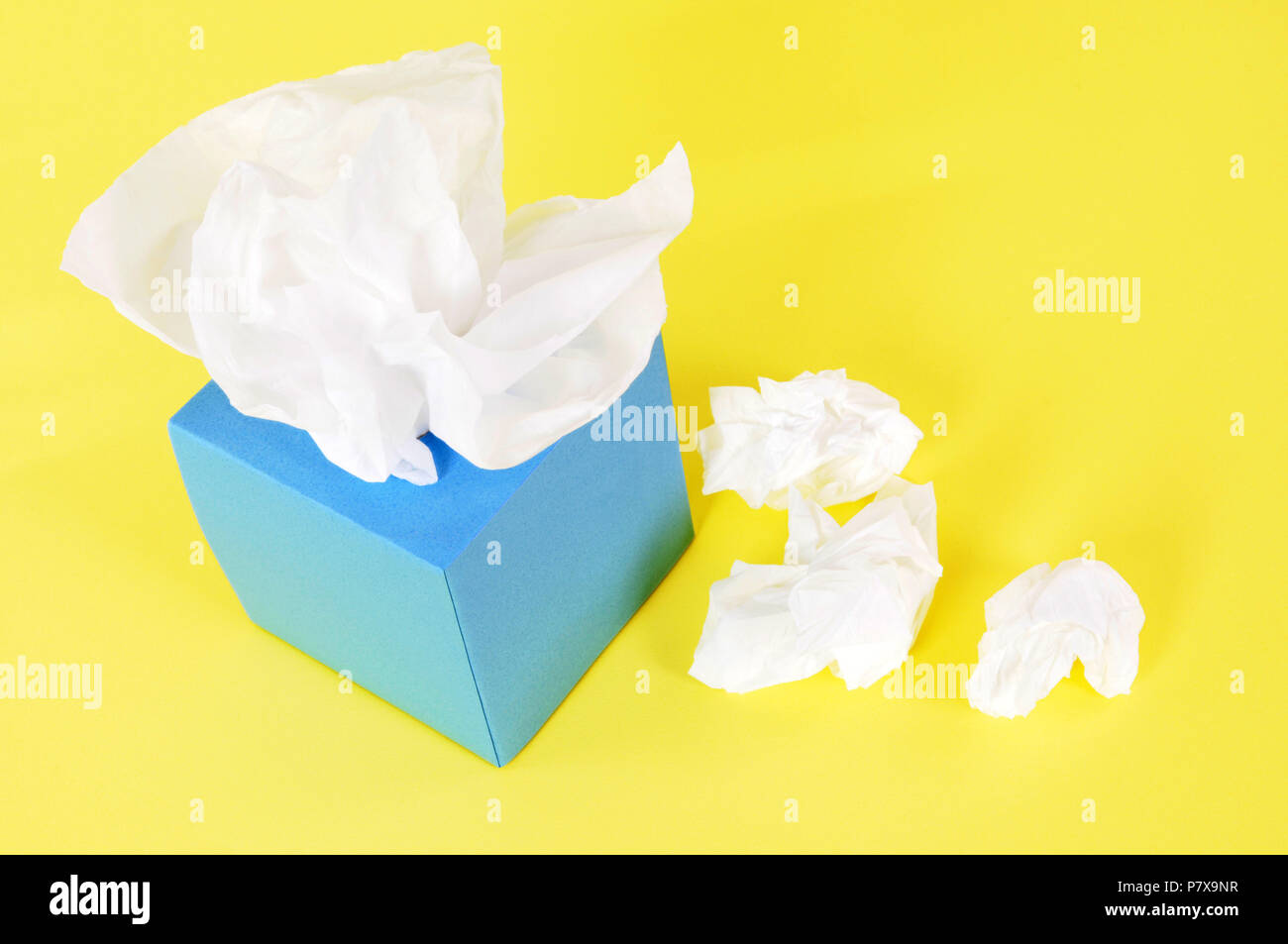 Kleenex style tissues in blank blue box on a yellow background Stock ...
