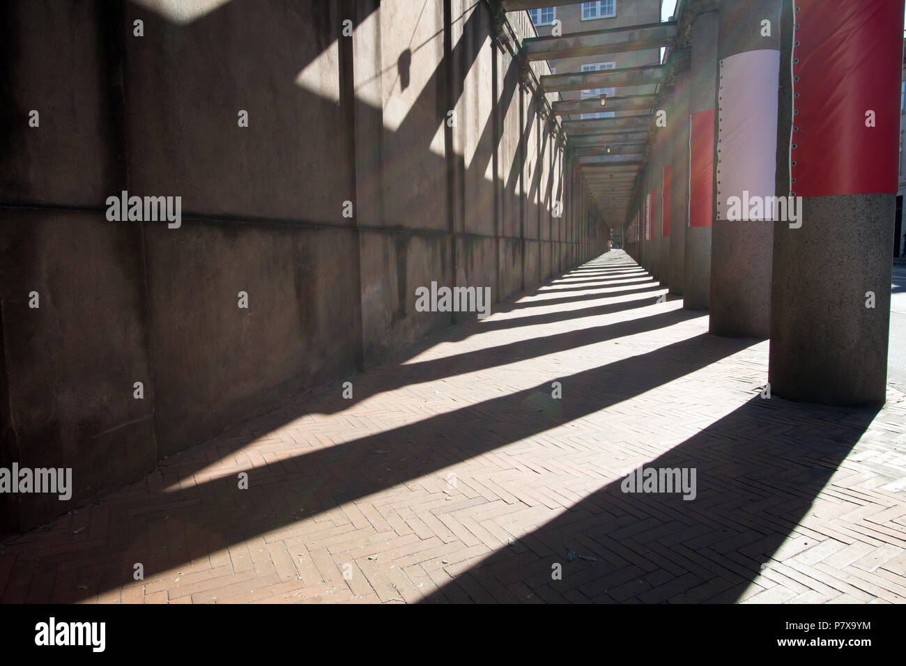 Long shadows on the pavement left by pillars and girders on a bright ...
