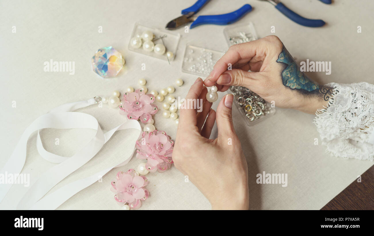 Girl fashion designer makes jewelry. Shooting close-up. She pushes the ...