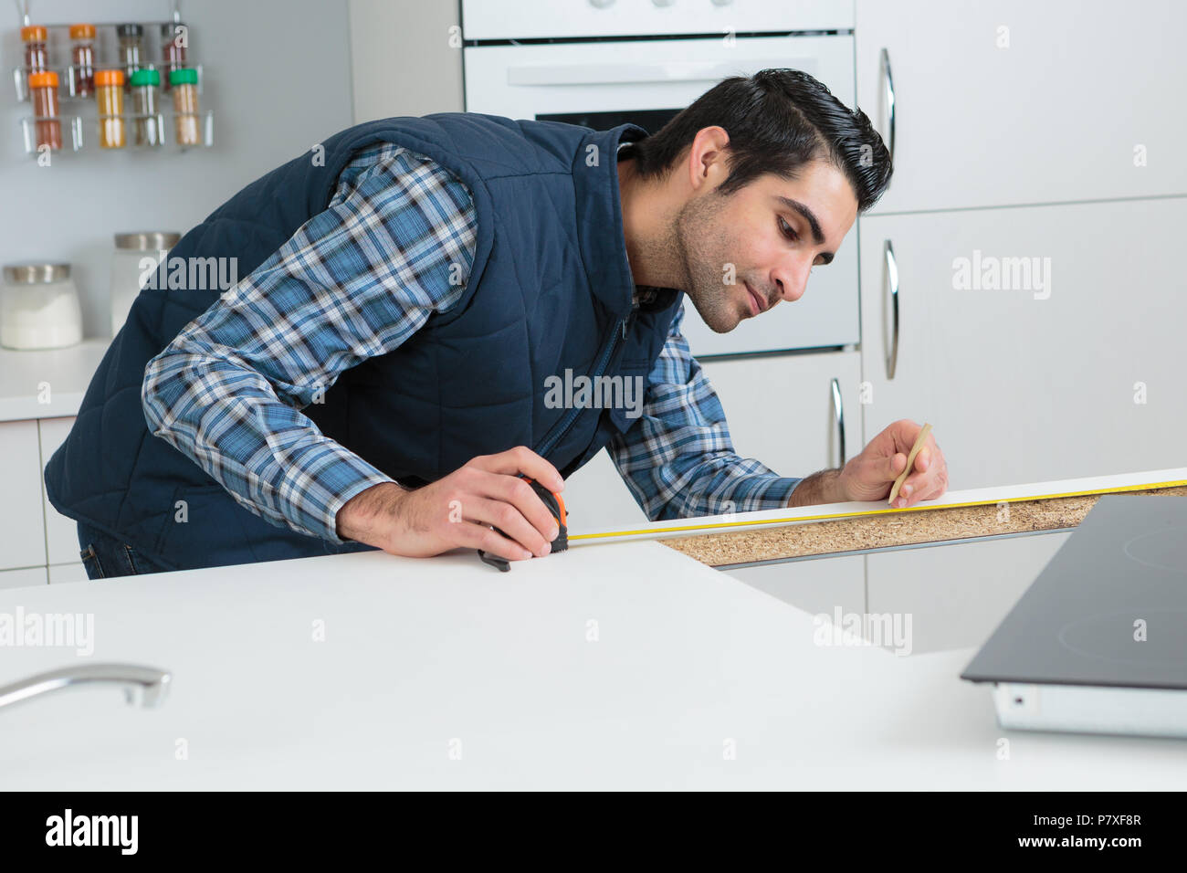 worker calculating measures on a kitchens construction Stock Photo - Alamy