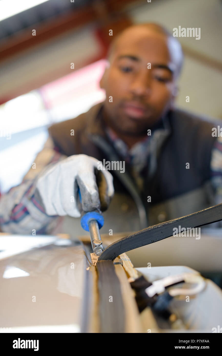 Man removing rubber windscreen beading Stock Photo - Alamy