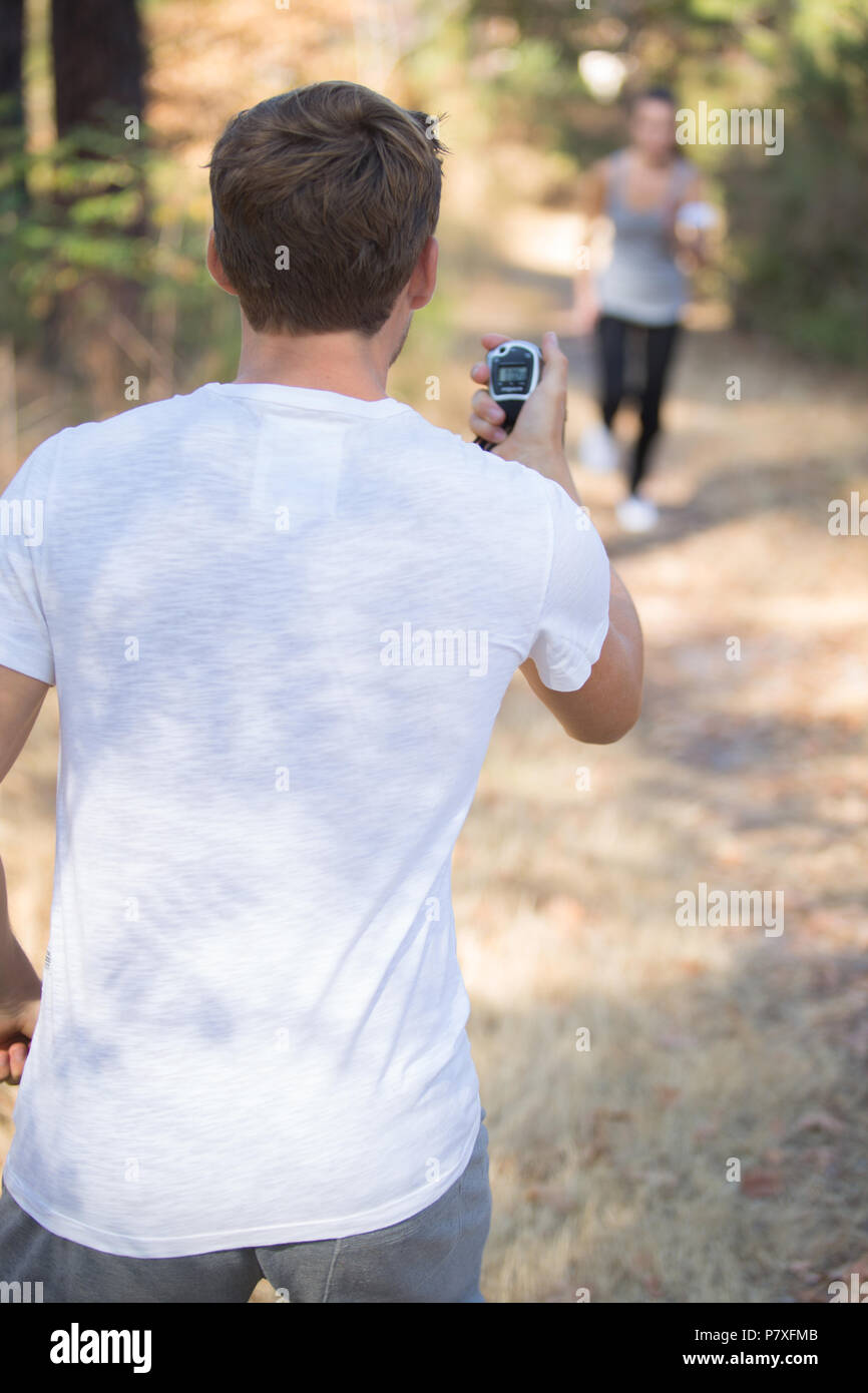 personal trainer timing a female runner Stock Photo - Alamy