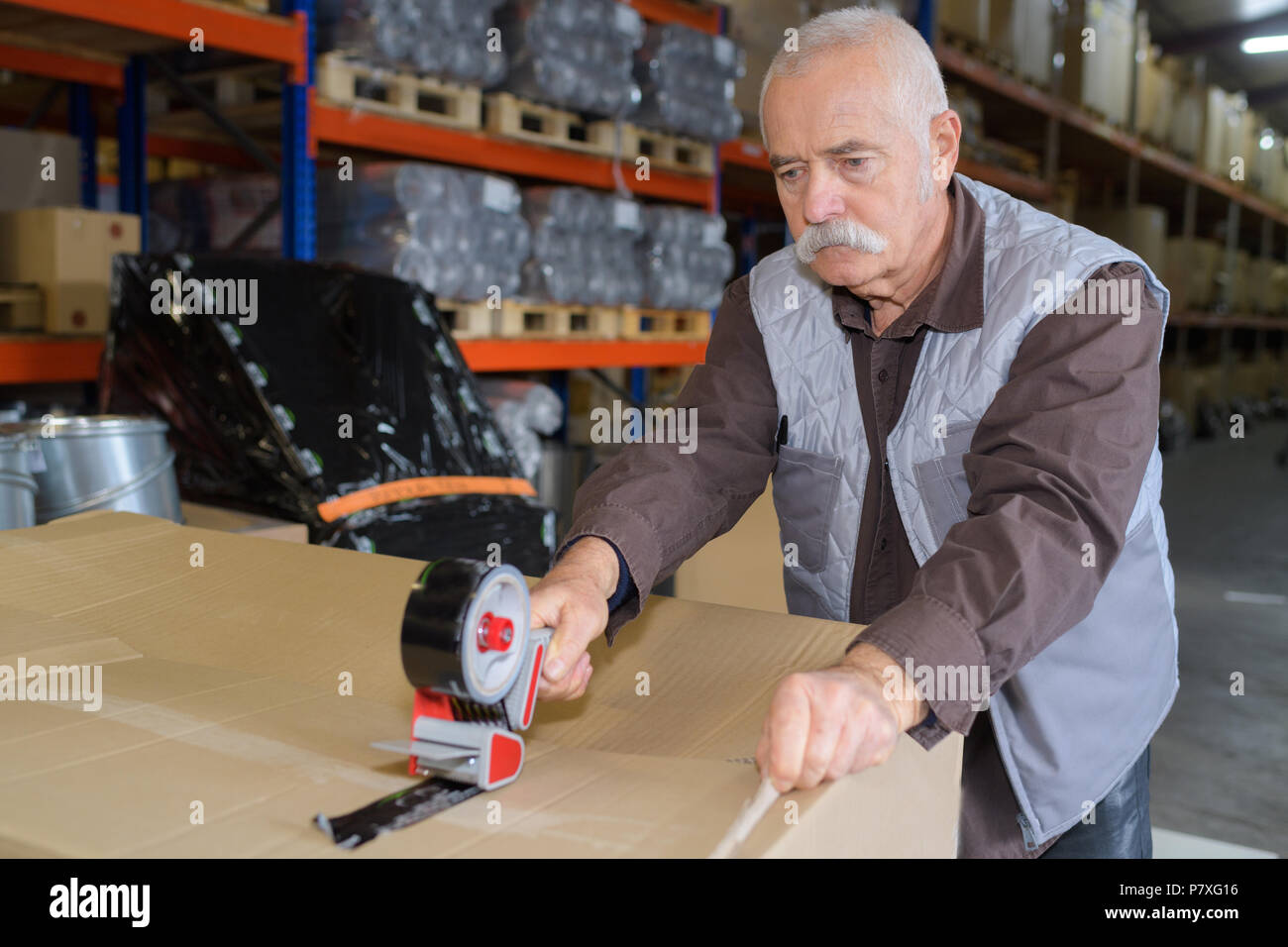 senior worker taping a box in warehouse Stock Photo - Alamy