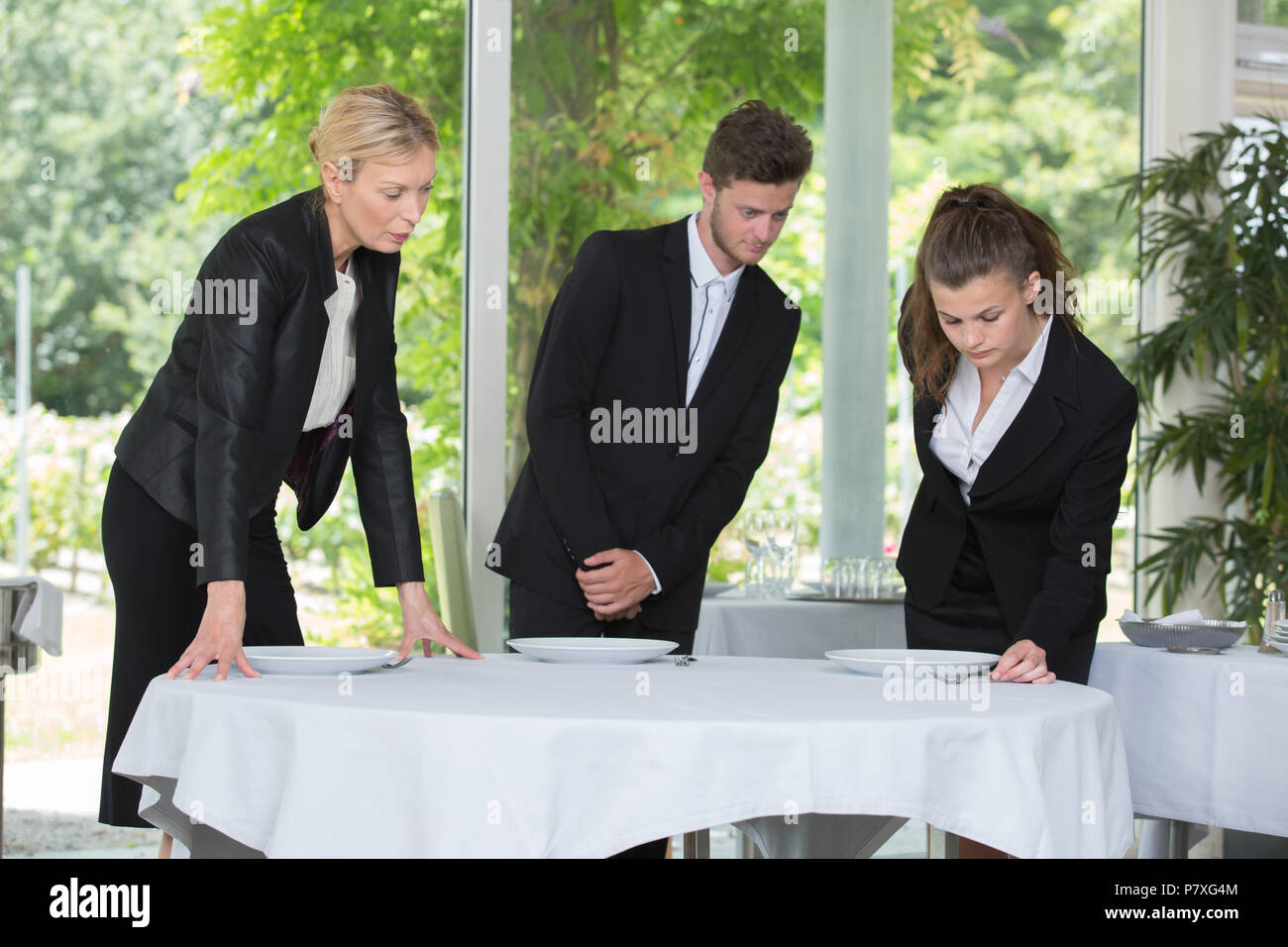 chier senior waitress and her team setting up the tables Stock Photo ...