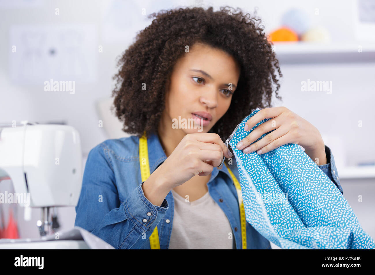 beautiful young designer cutting cloth while working in dressmaking ...