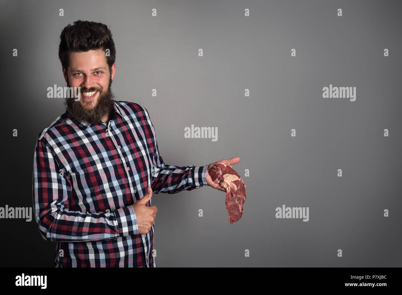 professional butcher smiling and holding raw meat. young chef ...