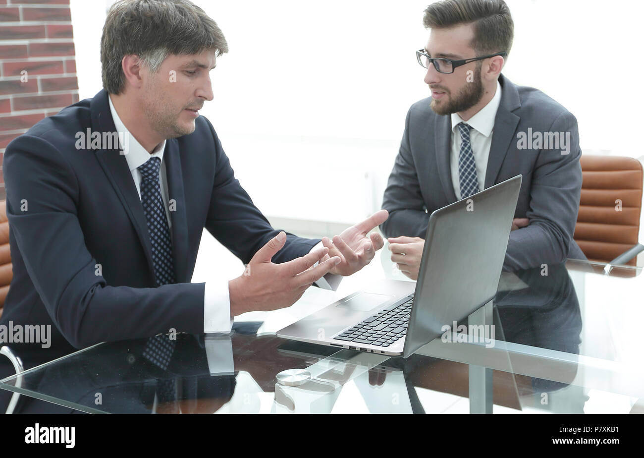 Two businessmen discussing tasks sitting at office table Stock Photo ...