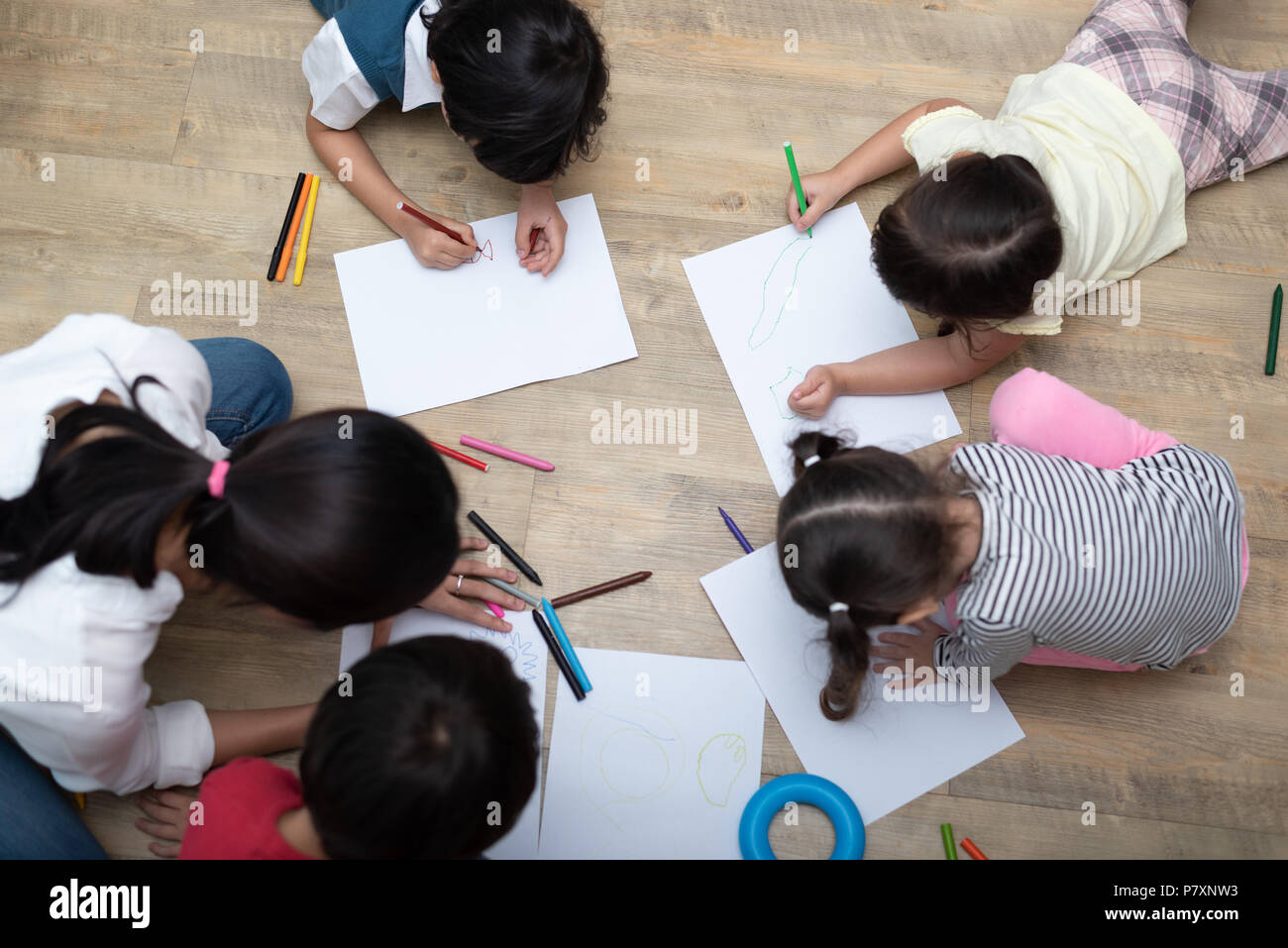 Group of preschool student and teacher drawing on paper in art class ...