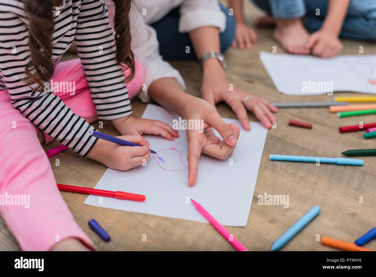 Closed up hands of mom teaching little children to drawing cartoon in ...