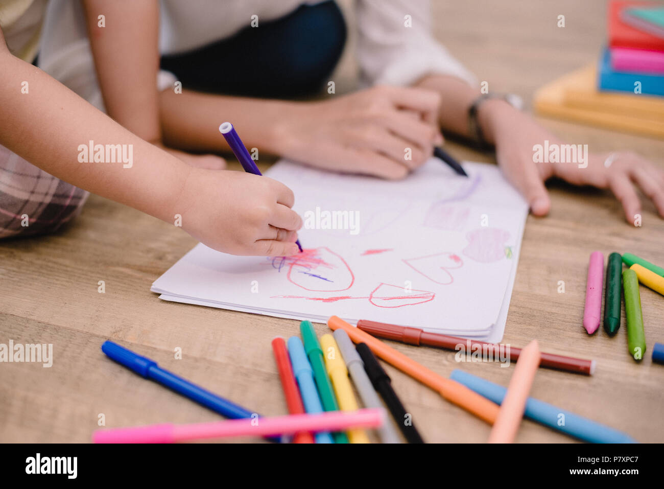Closed up hands of mom teaching little children to drawing cartoon in ...