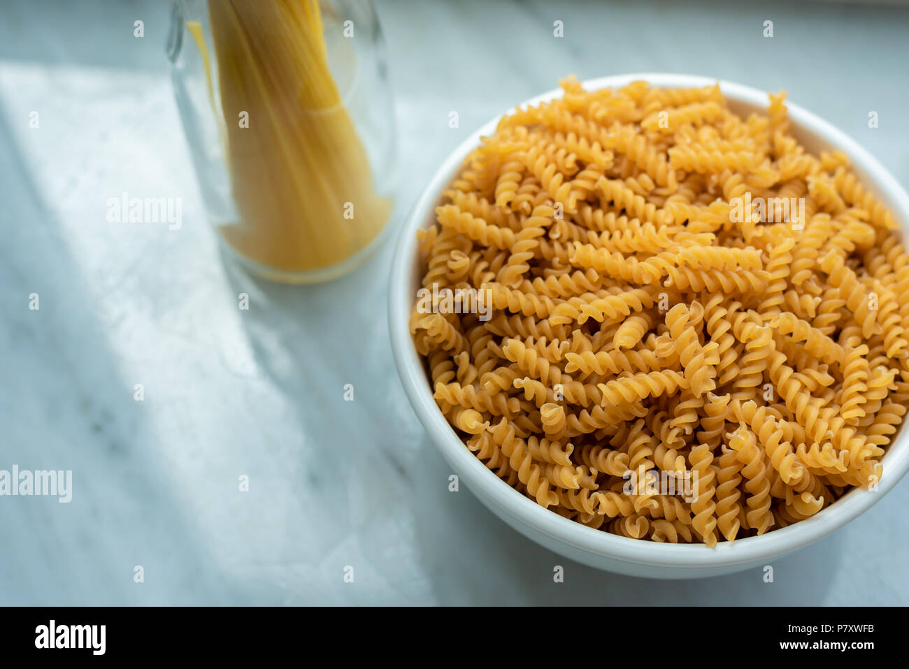 Top view of white bowl of spiral macaroni and tied spaghetti stand ...