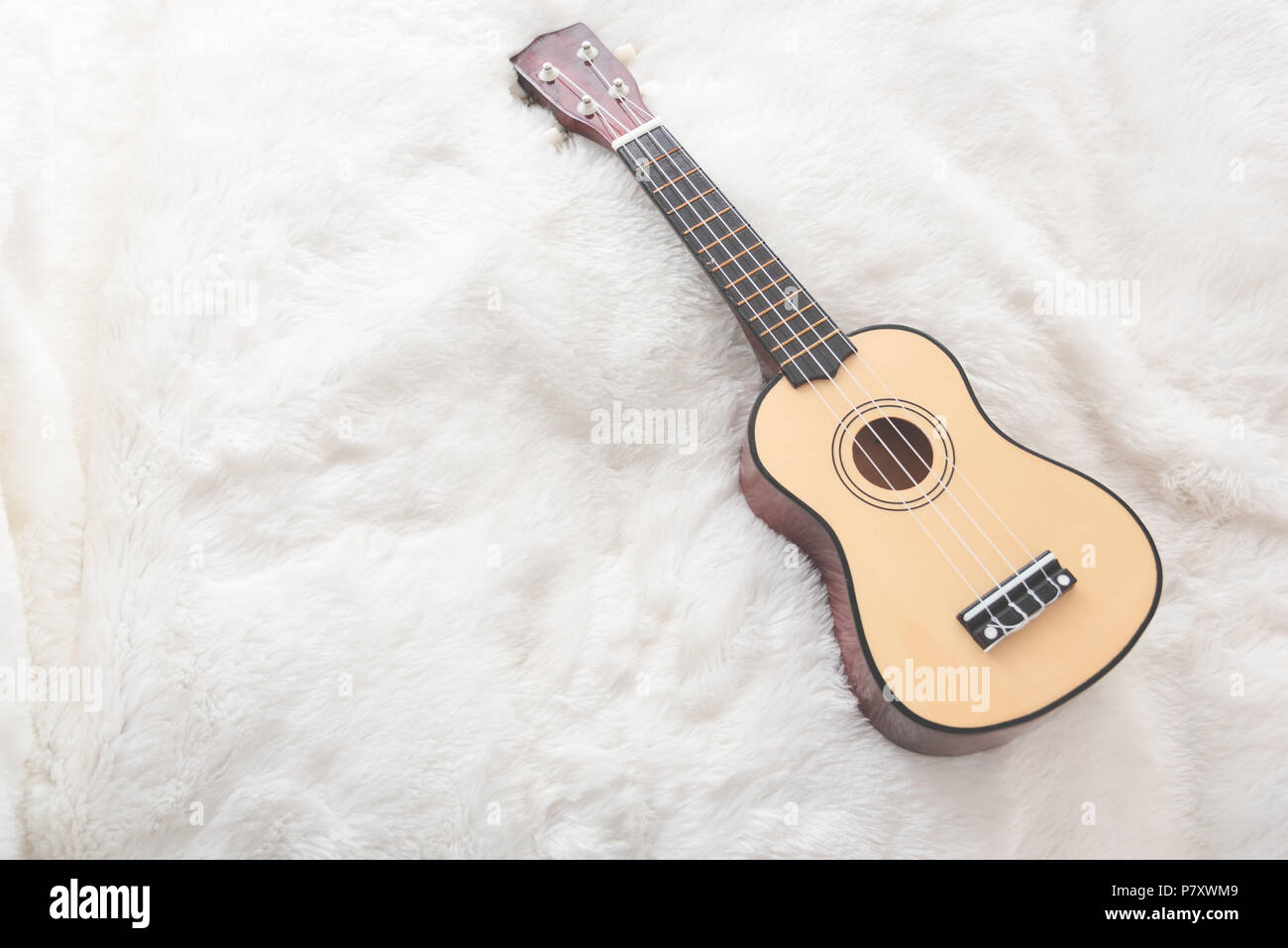 Small guitar on white wool. Musical instrument and leisure concept ...