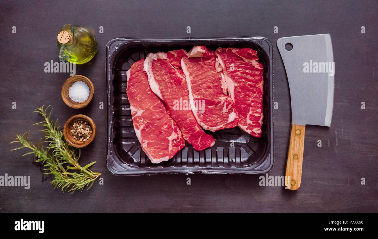 Raw New York strip steaks in black plastic meat packaging container ...