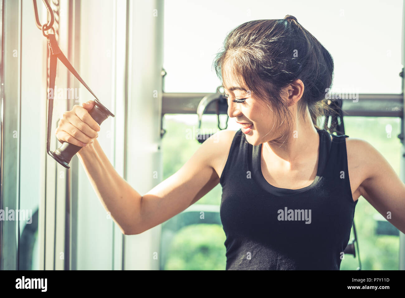 Asian young woman doing elastic rope exercises at cross fitness gym ...
