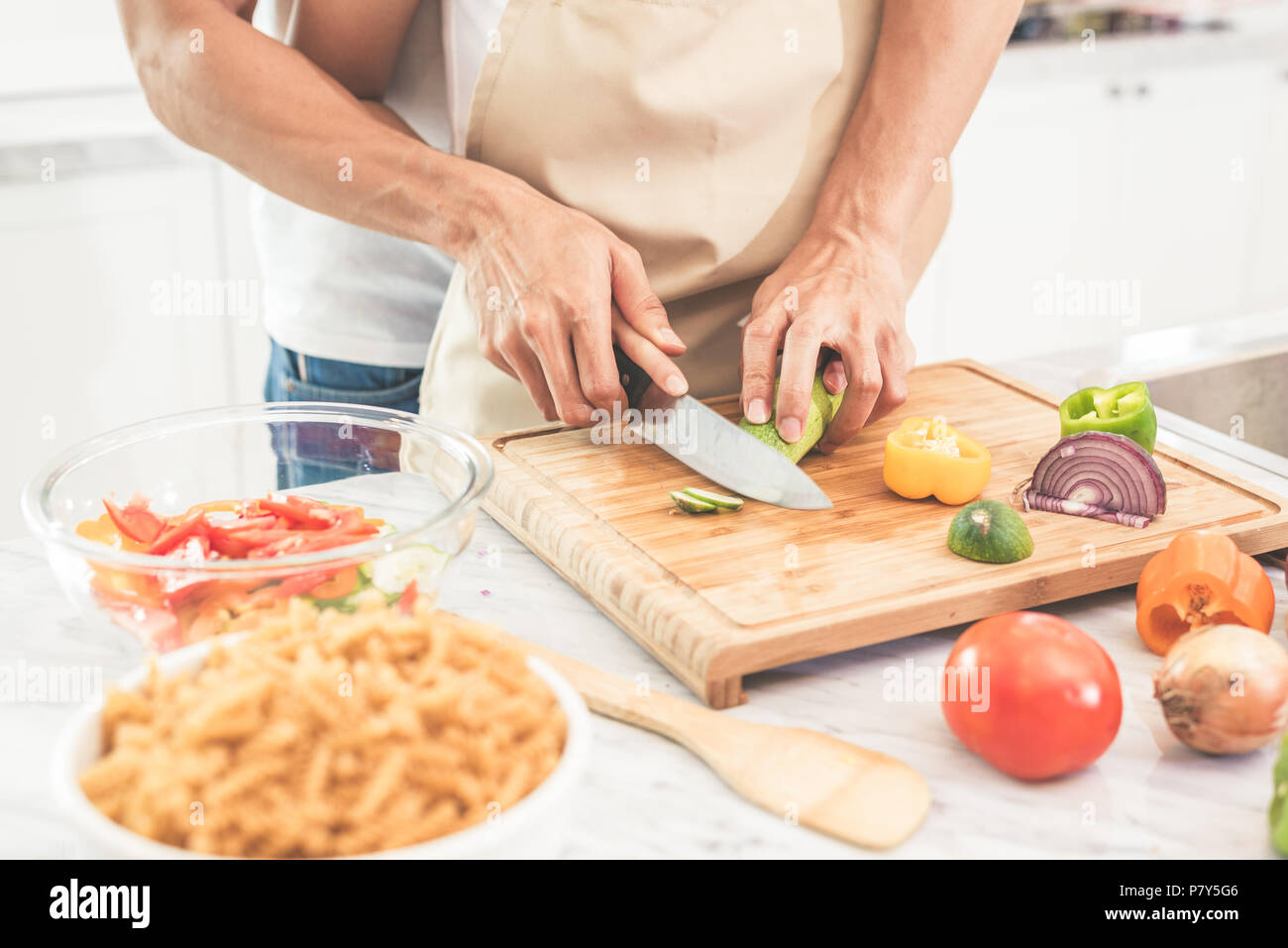 Hands of couple or lovers cooking and slicing vegetables with knife ...
