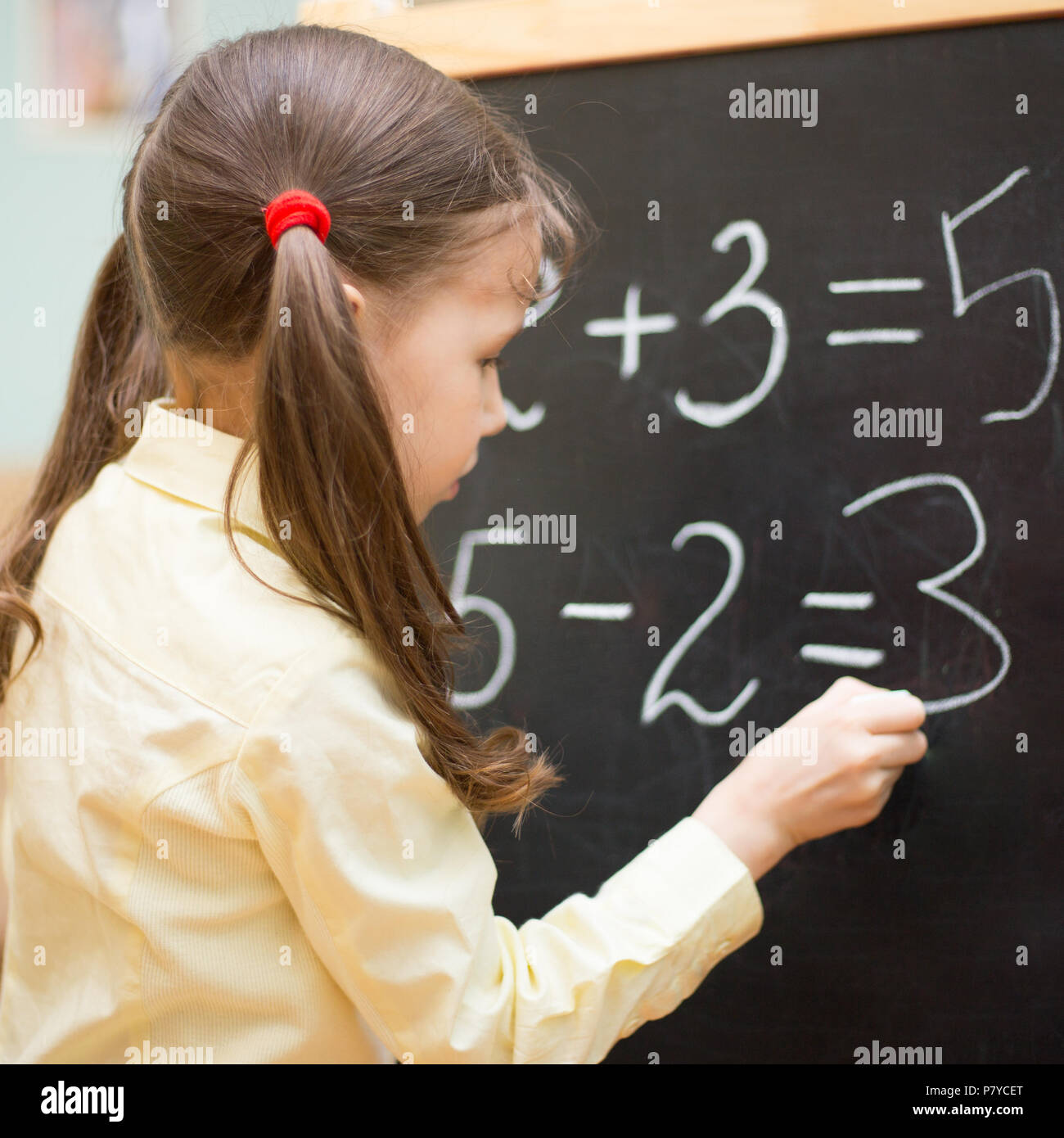 Little teacher. Beautiful young girl is teaching at home on blackboard ...