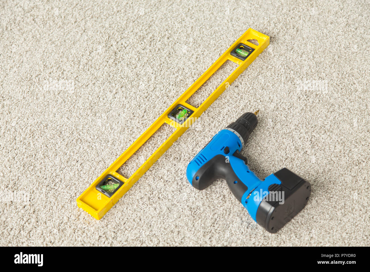 Builders level and drill on the floor, top view Stock Photo - Alamy