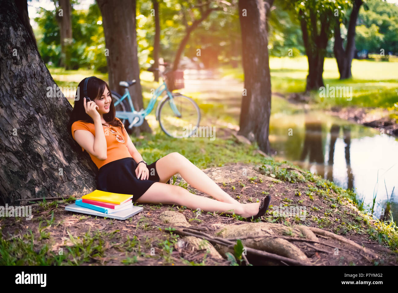 Woman relax under the tree in the park with headphones, relax concept ...
