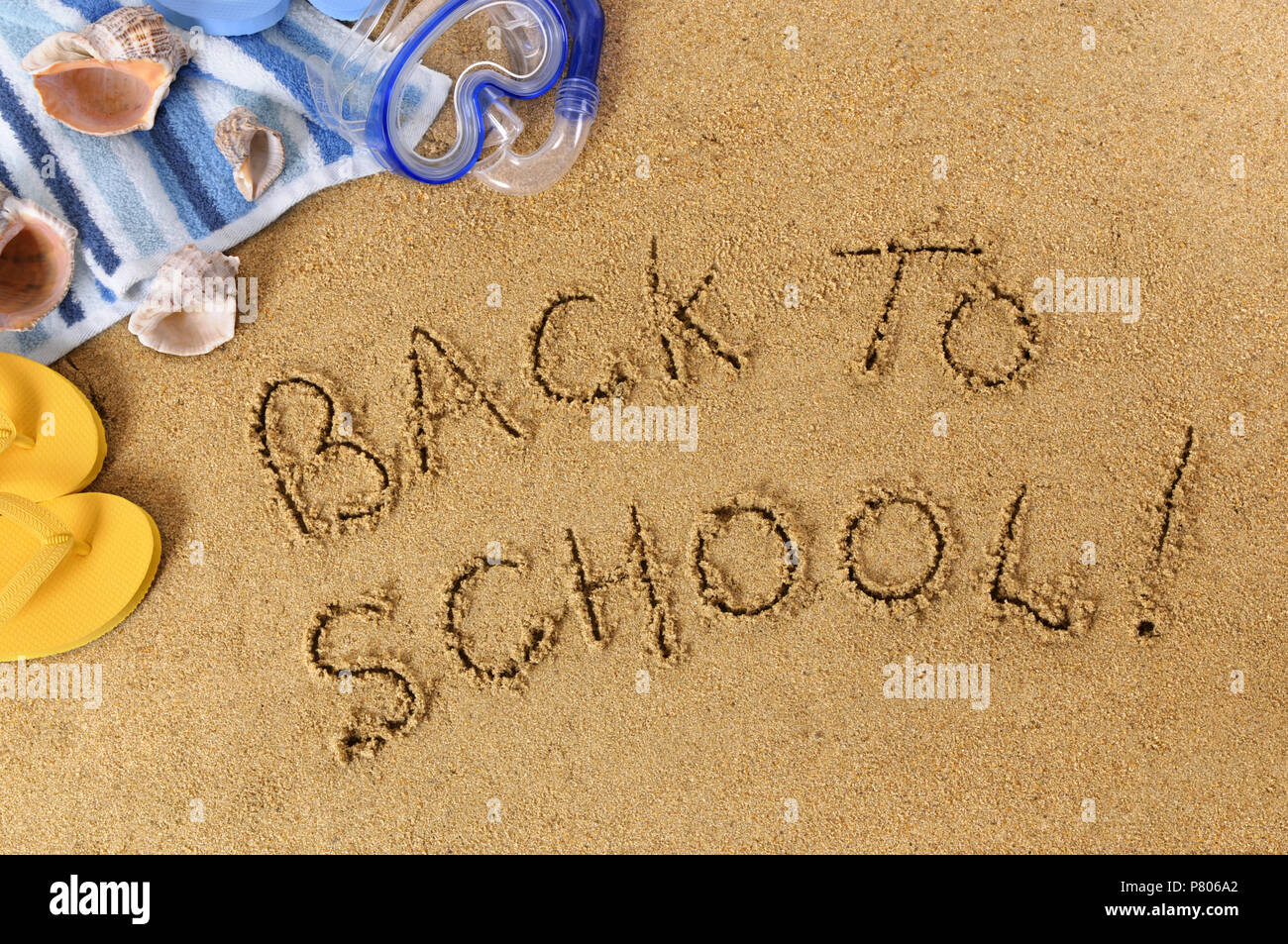 Back To School written on a beach with towel, seashells and flip flops ...