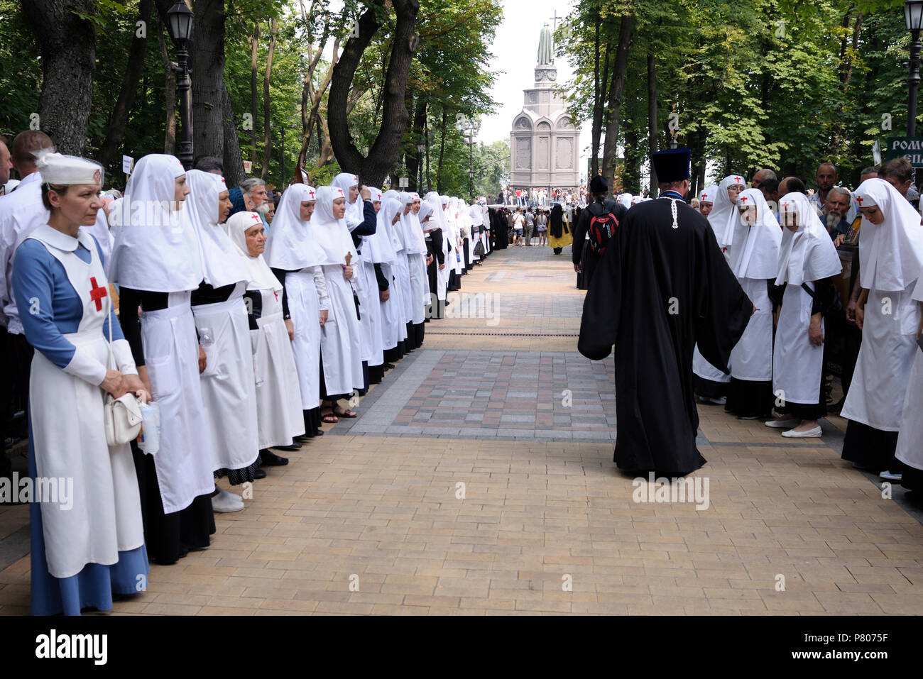 Churchman checking lines of nurses standing in a park before religious ...