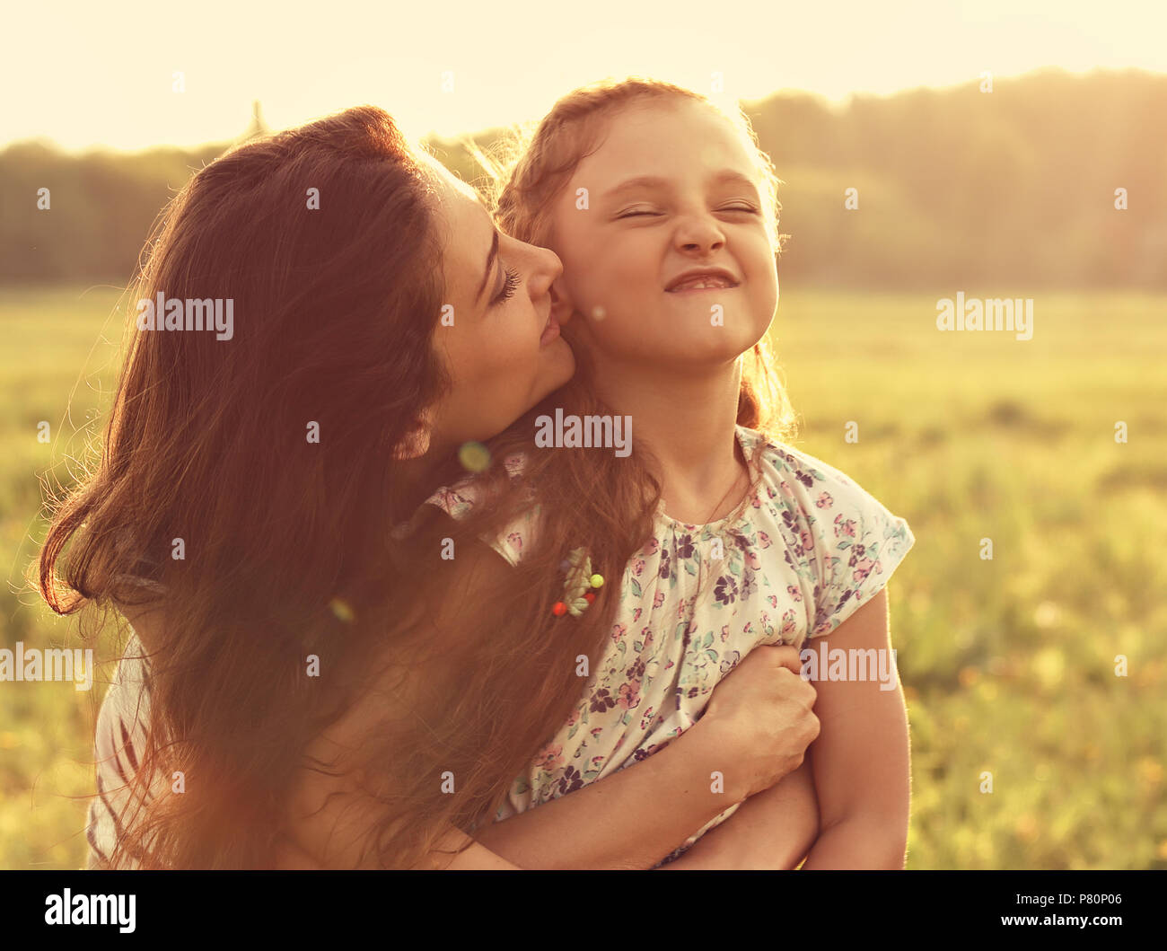 Happy enjoying mother hugging with her relaxing grimacing kid girl on ...
