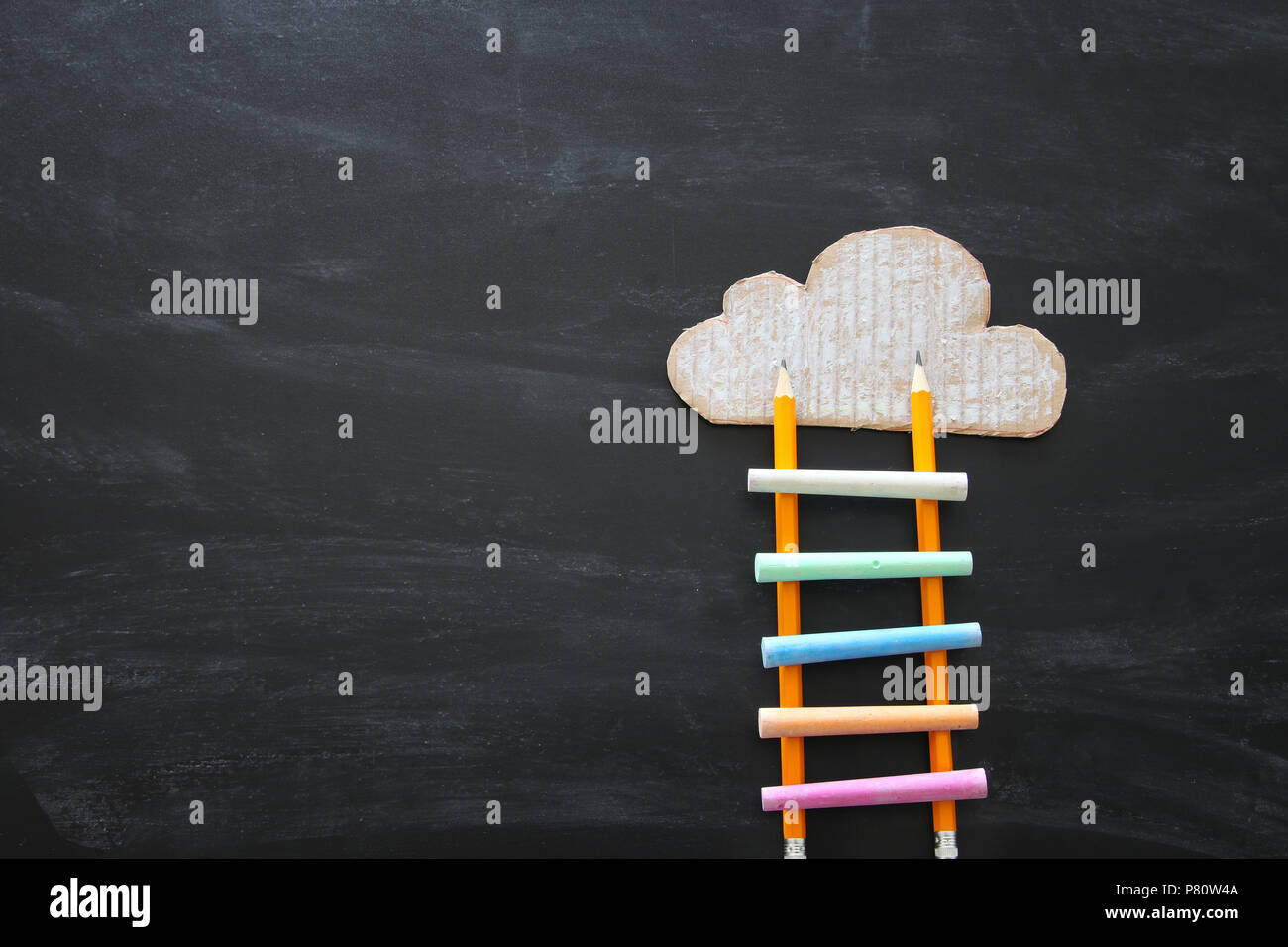 ladder made of colorful chalks and pencils next to clouds over ...