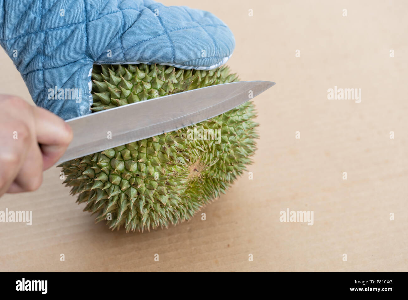 Hand using knife to peel durian shell which has a lot of thorns ...