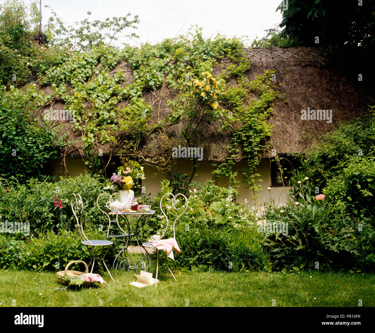 Metal table and chairs on lawn in front of dilapidated cottage with ...