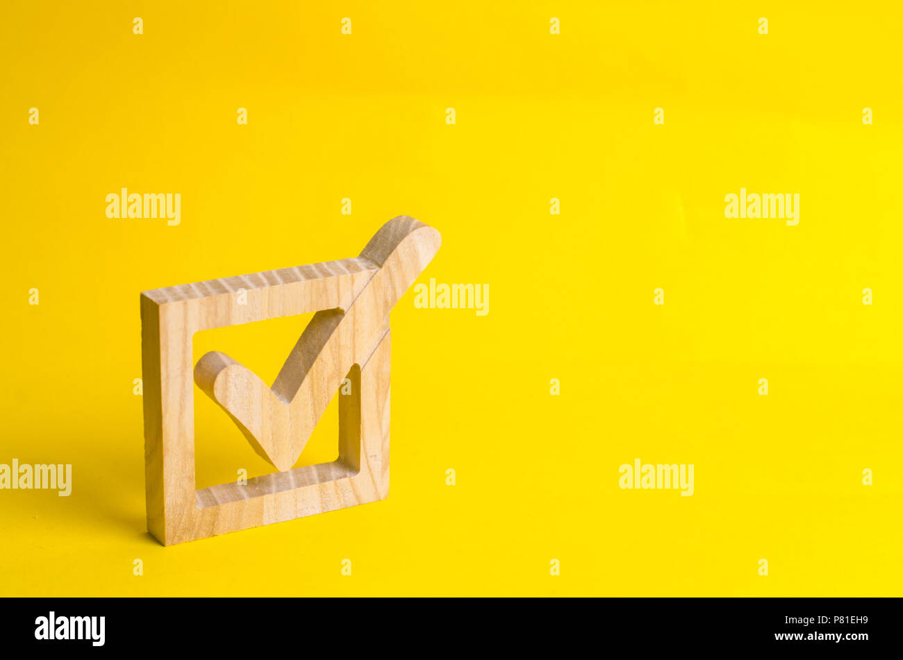 A wooden checkmark in the box on a yellow background. The concept of ...