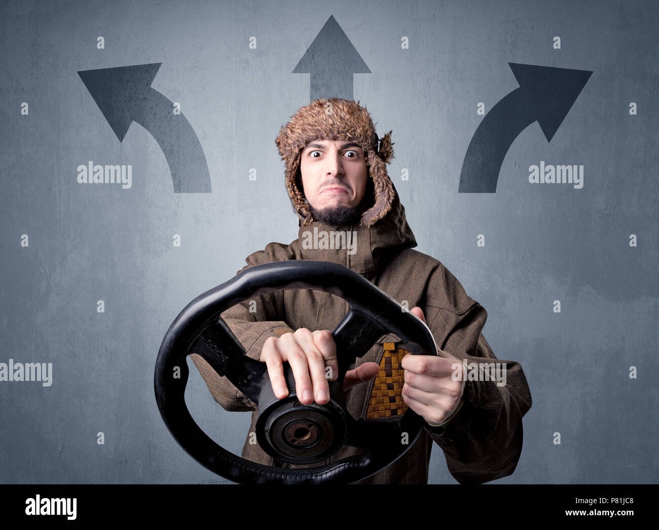 Young man holding black steering wheel with three arrows above his head ...
