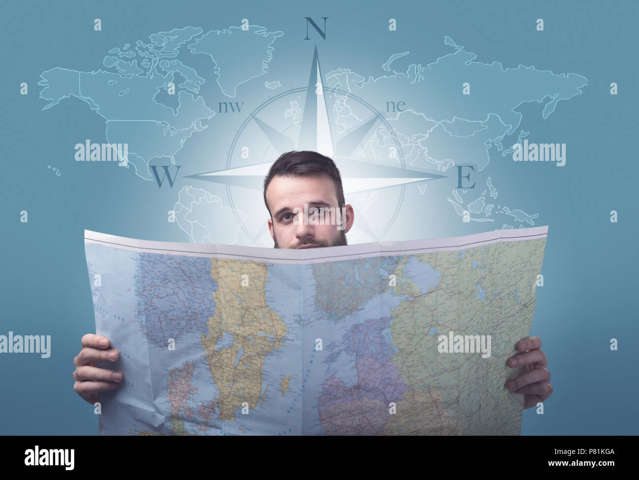 Handsome young man holding a map with a world map and a compass behind ...