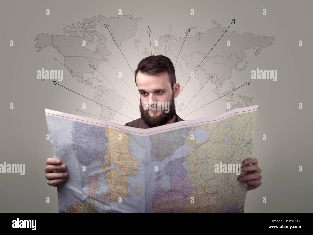 Handsome young man holding a map with world map and arrows behind him ...