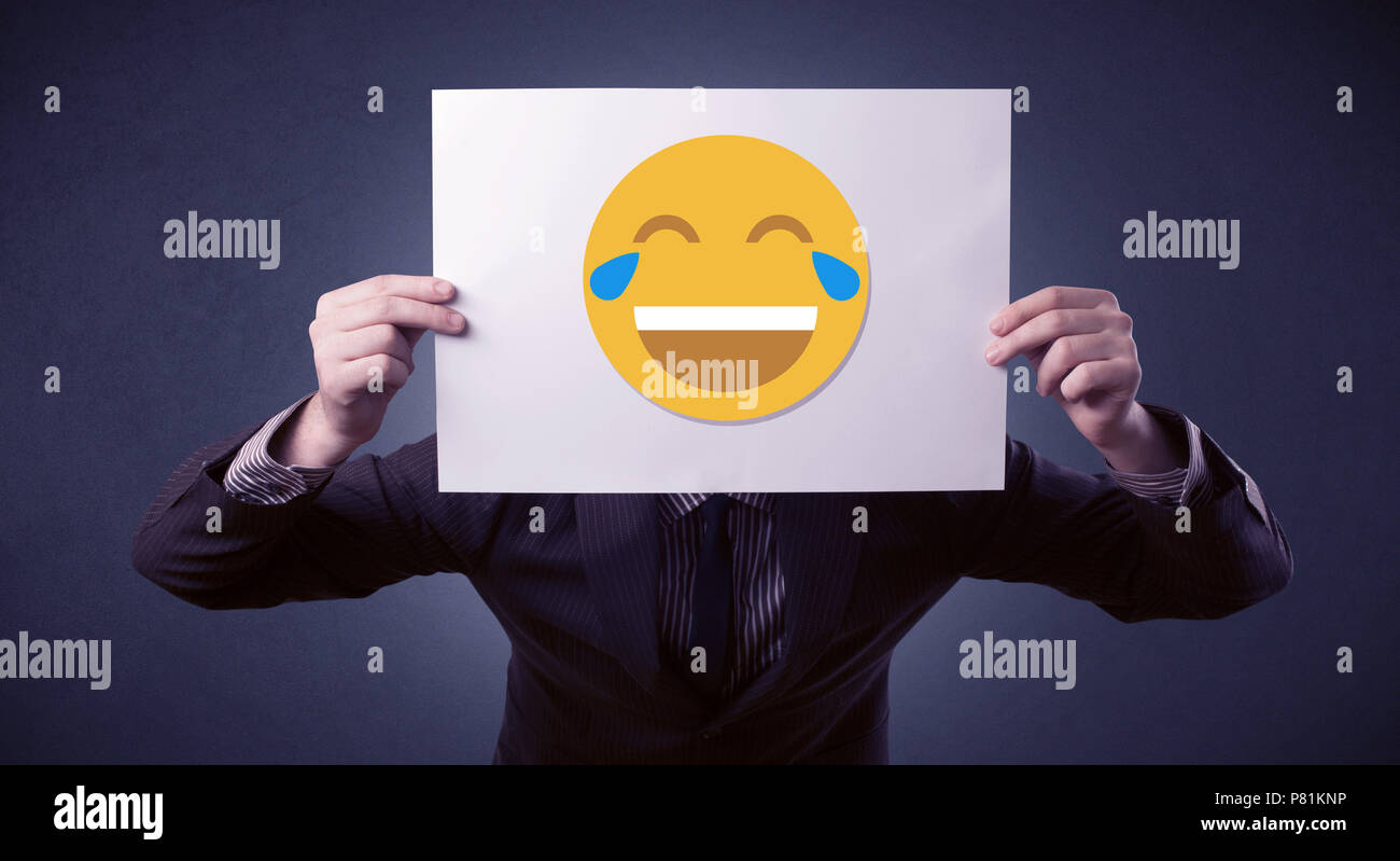 Young businessman hiding behind a laughing emoticon on cardboard Stock ...