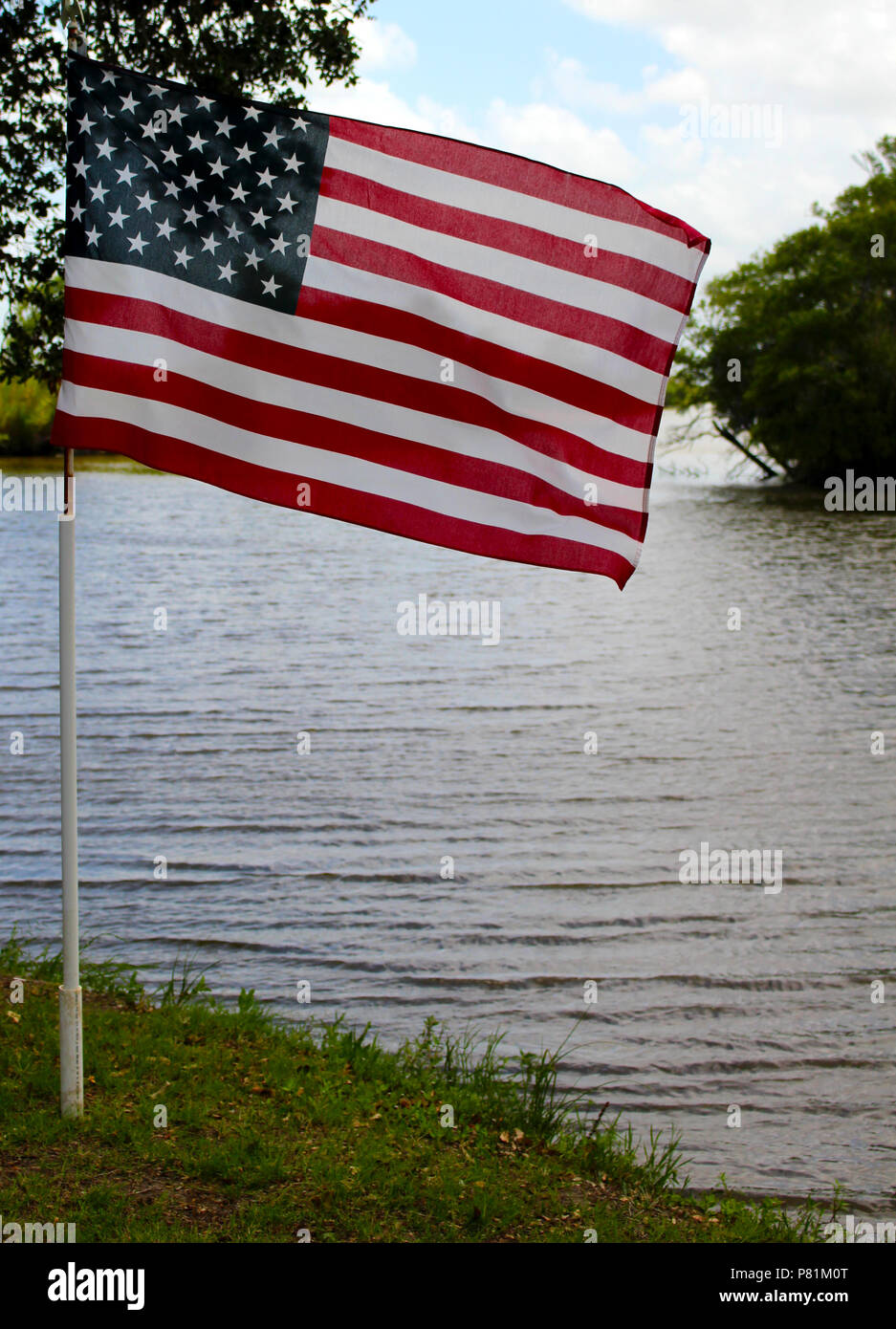 American flag waving in front of river Stock Photo - Alamy