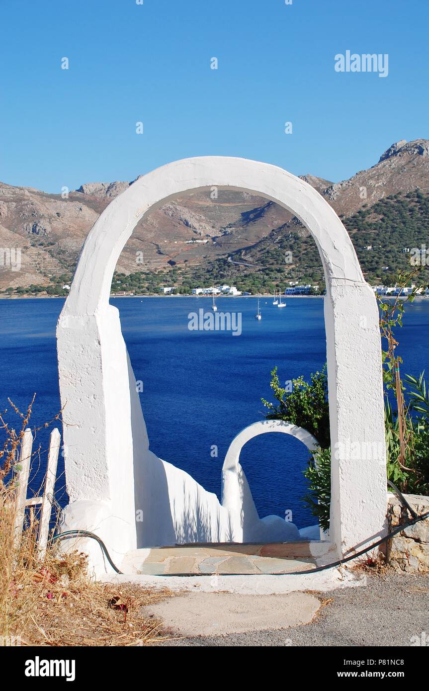 A white archway frames Livadia harbour on the Greek island of Tilos on ...