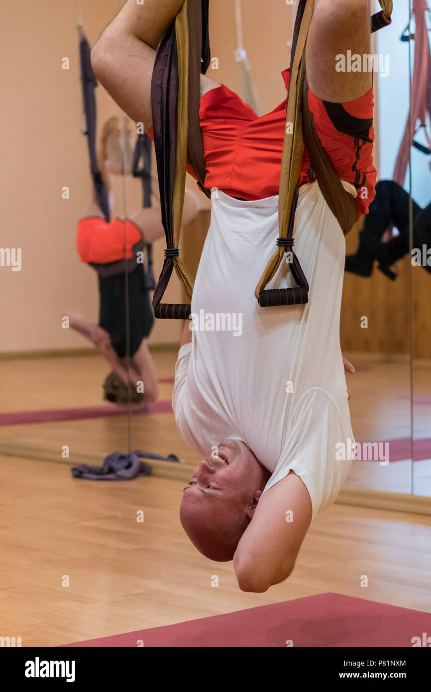 Anti-gravity Yoga, man doing yoga exercises. the man is hanging upside ...