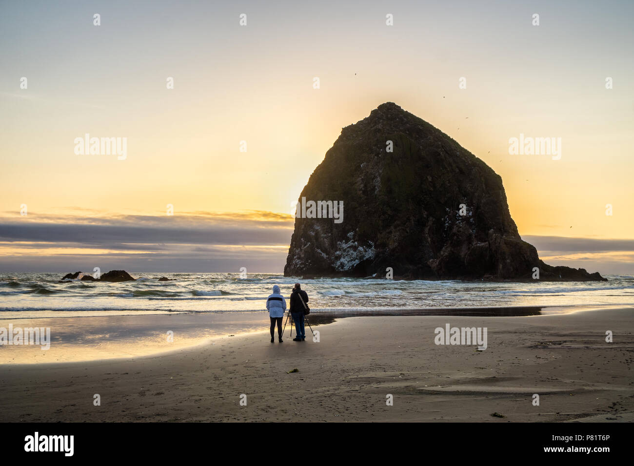Photographer with tripod waiting for sunset at Haystack Rock, iconic ...