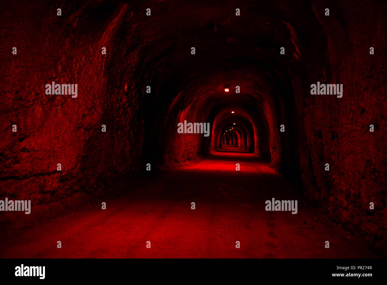 Deep red tunnel with spotlights in the rock Stock Photo - Alamy