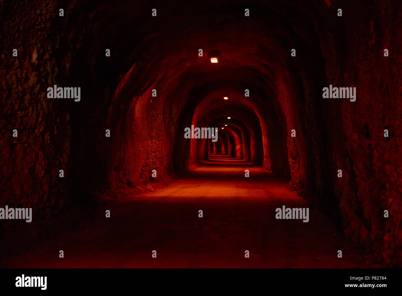 Deep red tunnel with spotlights in the rock Stock Photo - Alamy