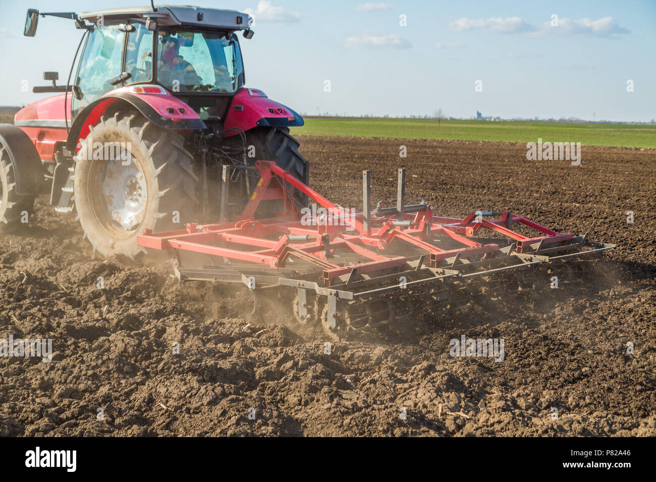 Farmer in tractor preparing land with seedbed cultivator as part of pre ...