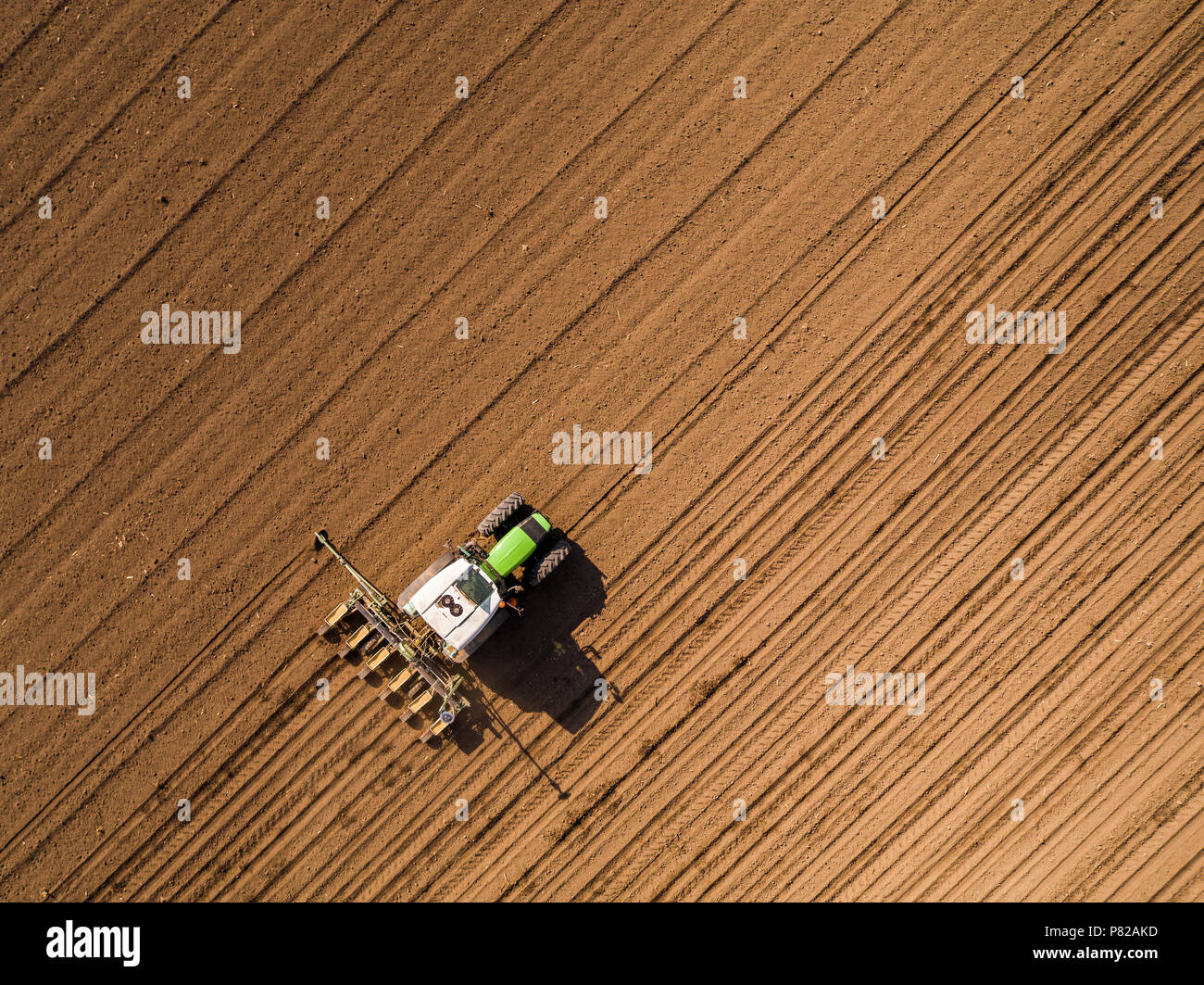 Aerial shot of a farmer seeding, sowing crops at field. Sowing is the ...