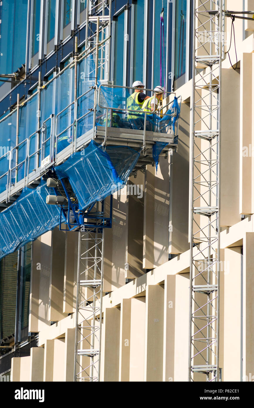 Workmen on a mobile inspection platform inspecting the exterior of a ...