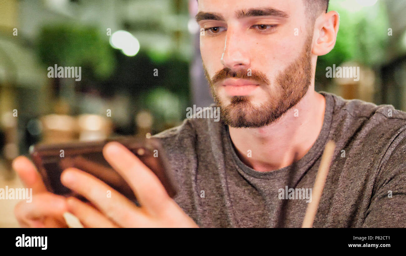 Young man outside at night watching video on phone Stock Photo - Alamy