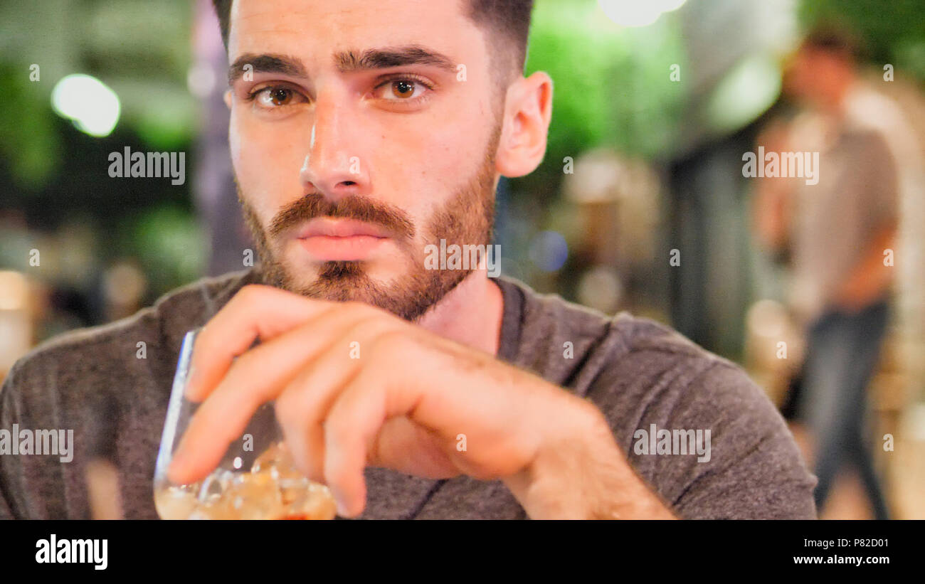 Young man drinking cocktail outside at night Stock Photo - Alamy